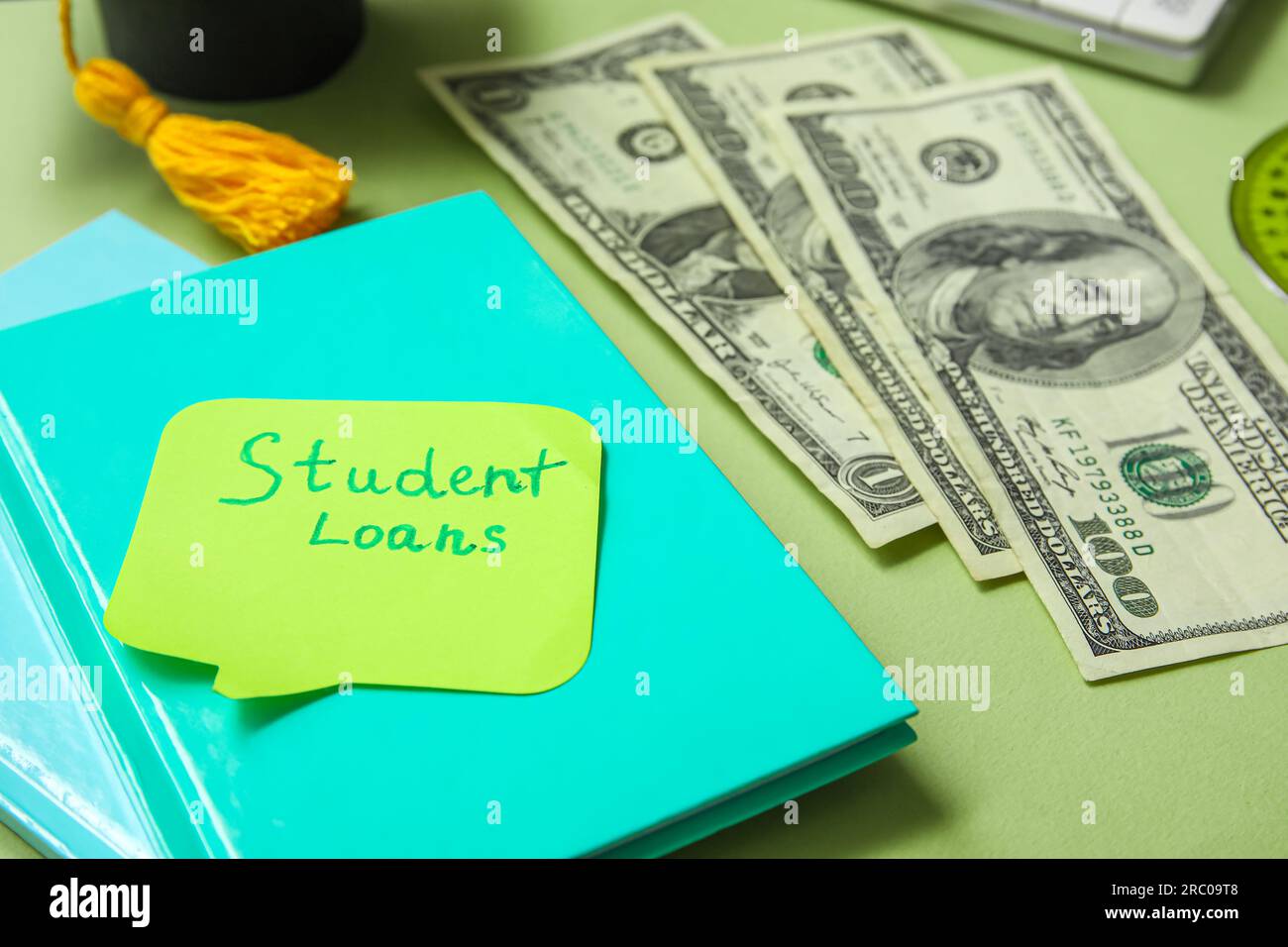Sticky note with text STUDENT LOANS, notebook and dollar banknotes on ...