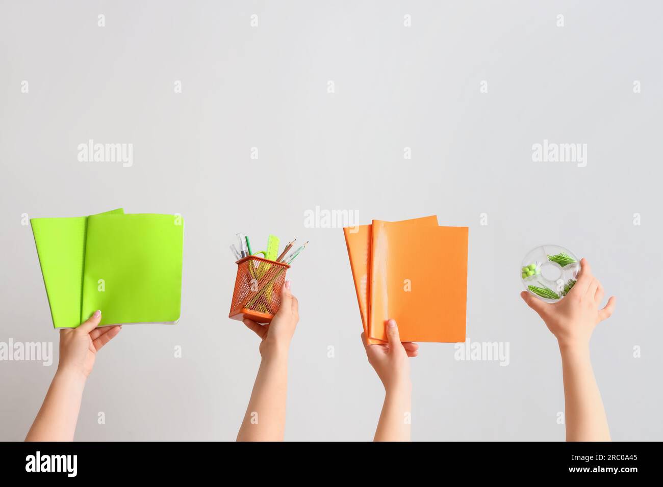 Female hands holding school supplies on grey background Stock Photo - Alamy