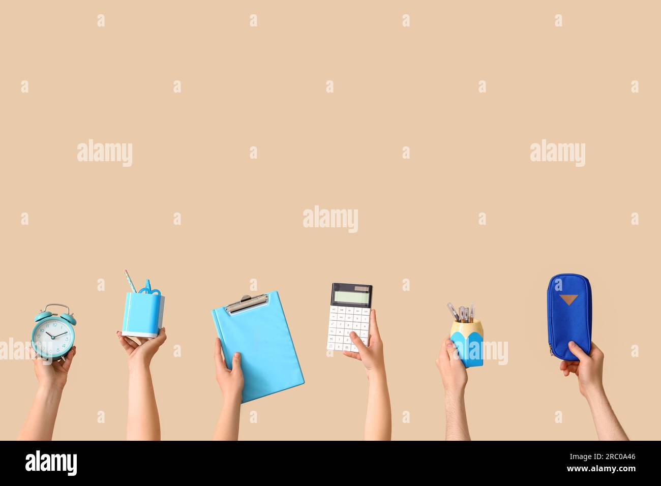 Many hands holding school supplies on beige background Stock Photo - Alamy