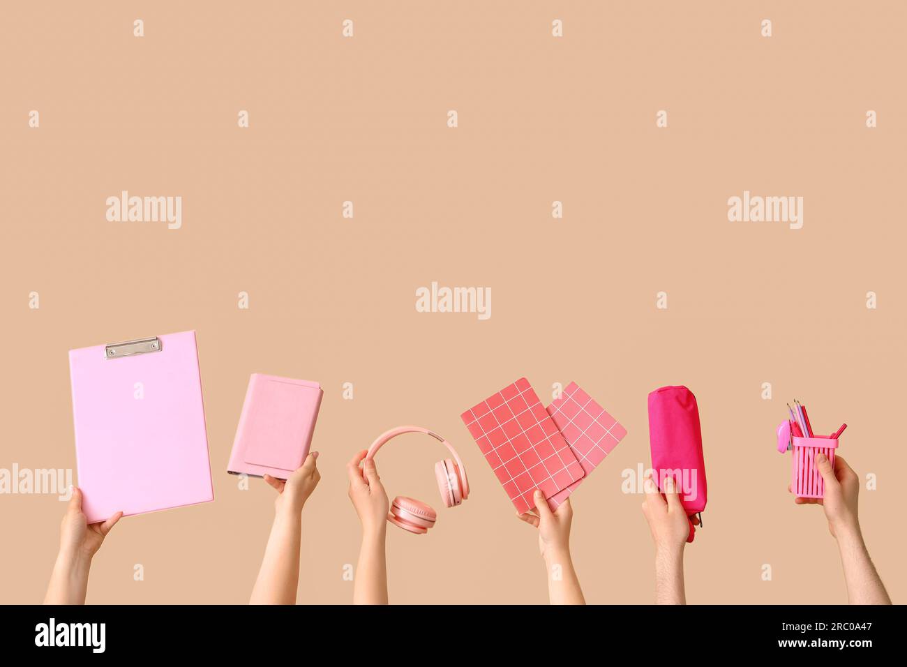 Many hands holding school supplies on beige background Stock Photo - Alamy