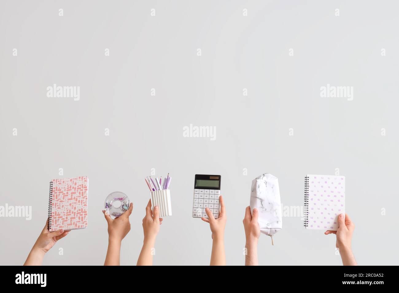 Many hands holding school supplies on grey background Stock Photo - Alamy