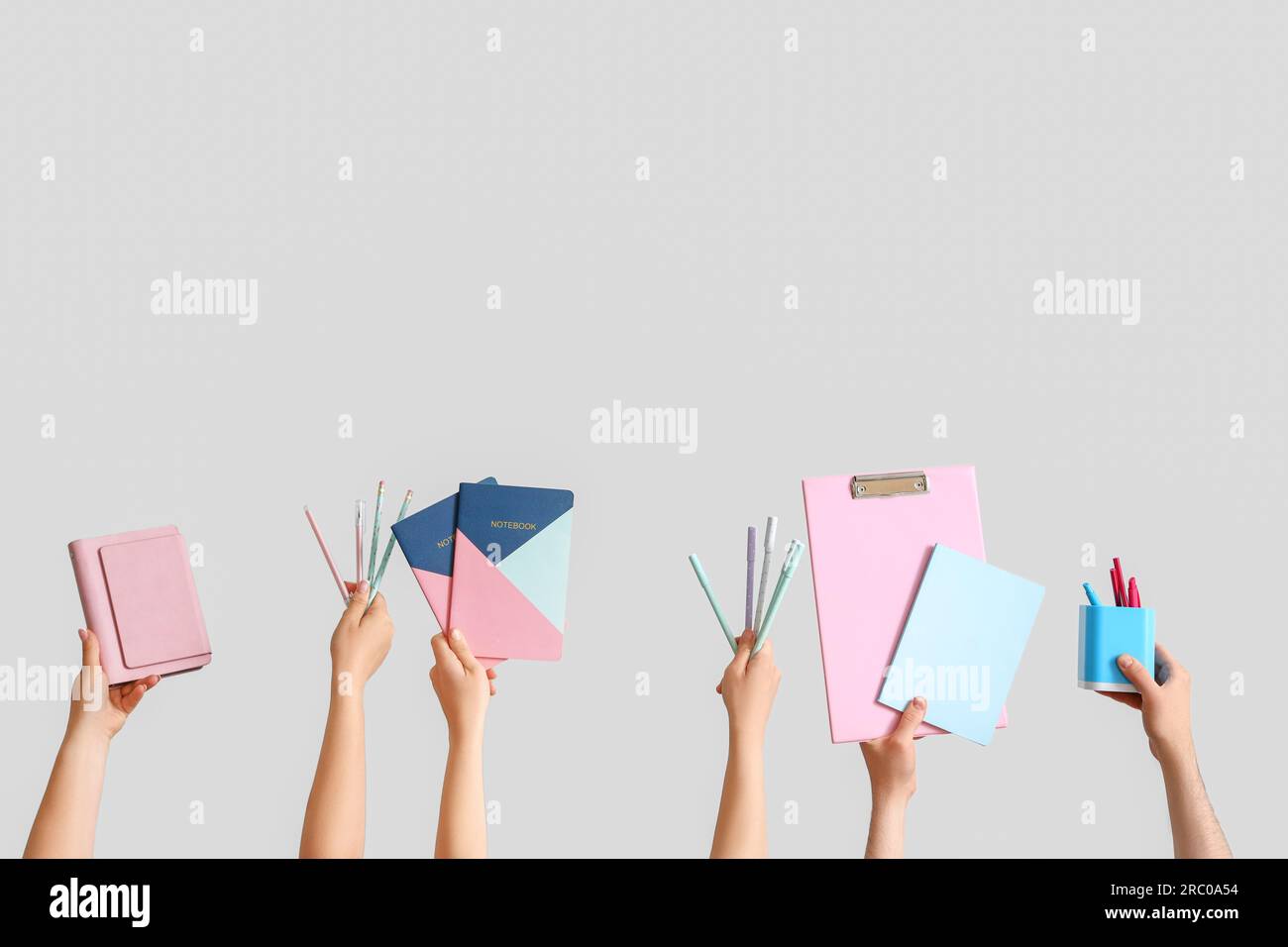 Many hands holding school supplies on grey background Stock Photo - Alamy