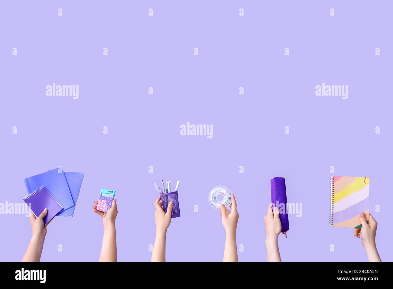 Many hands holding school supplies on lilac background Stock Photo - Alamy