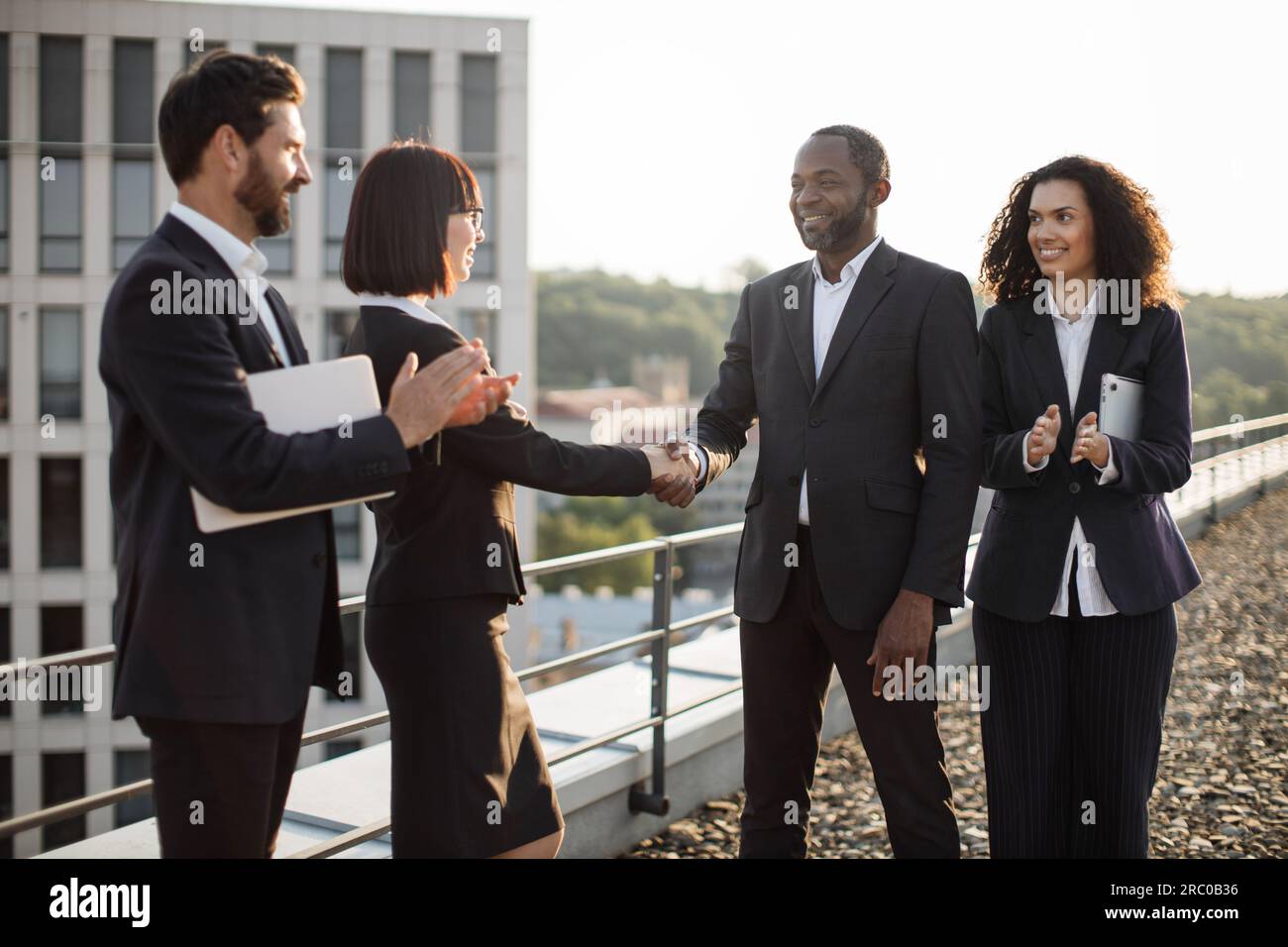 Four elegant stylish corporate leaders shaking hands after successful ...