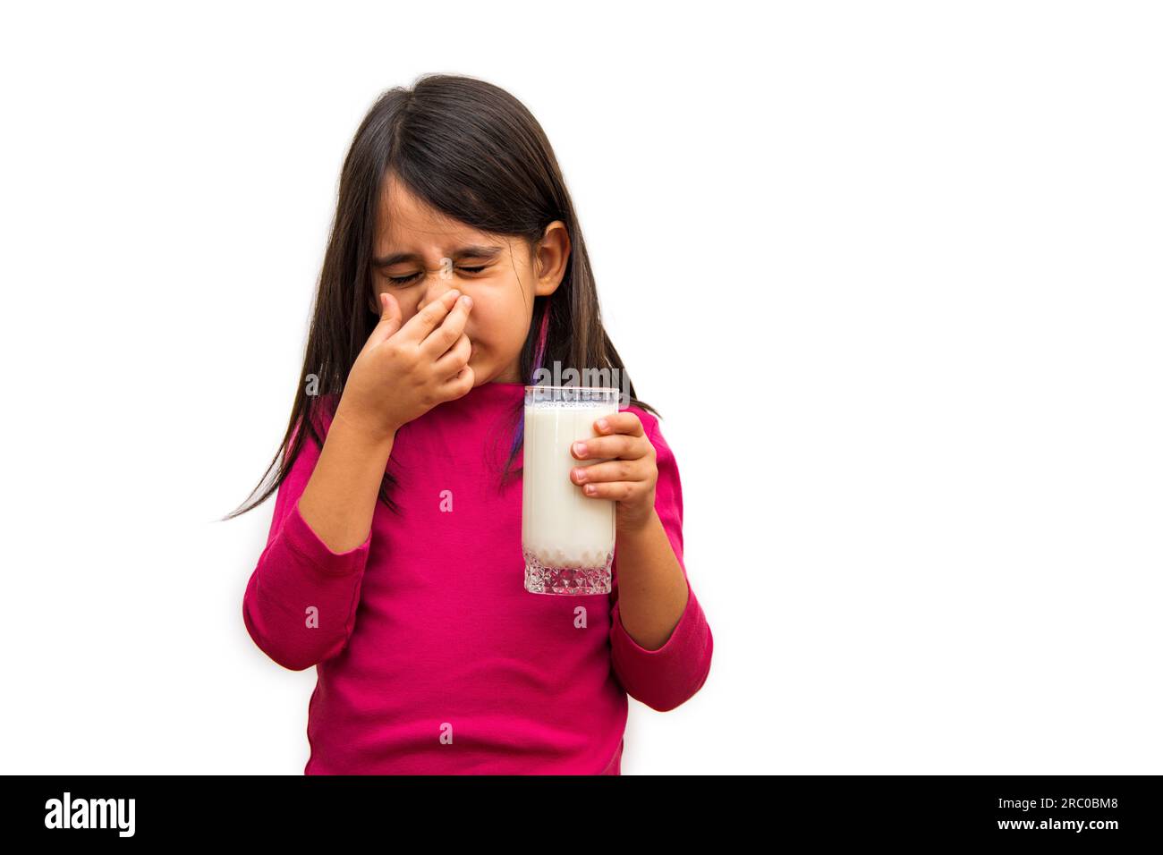 Little girl bothered by the smell of milk is covering her nose on a ...