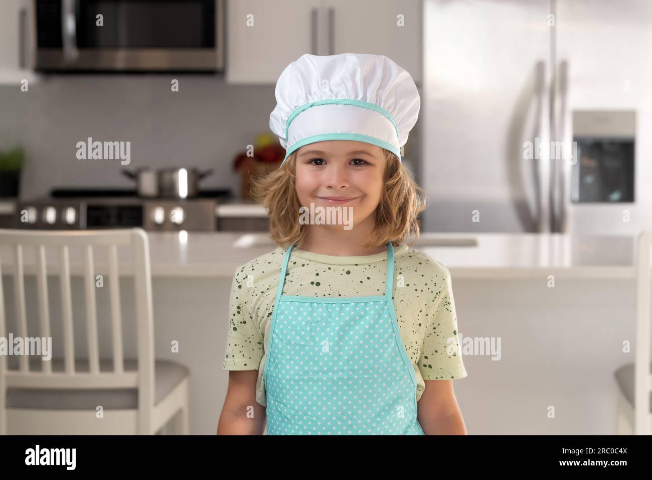 Portrait of funny child chef in kitchen. Child chef cook prepares food ...