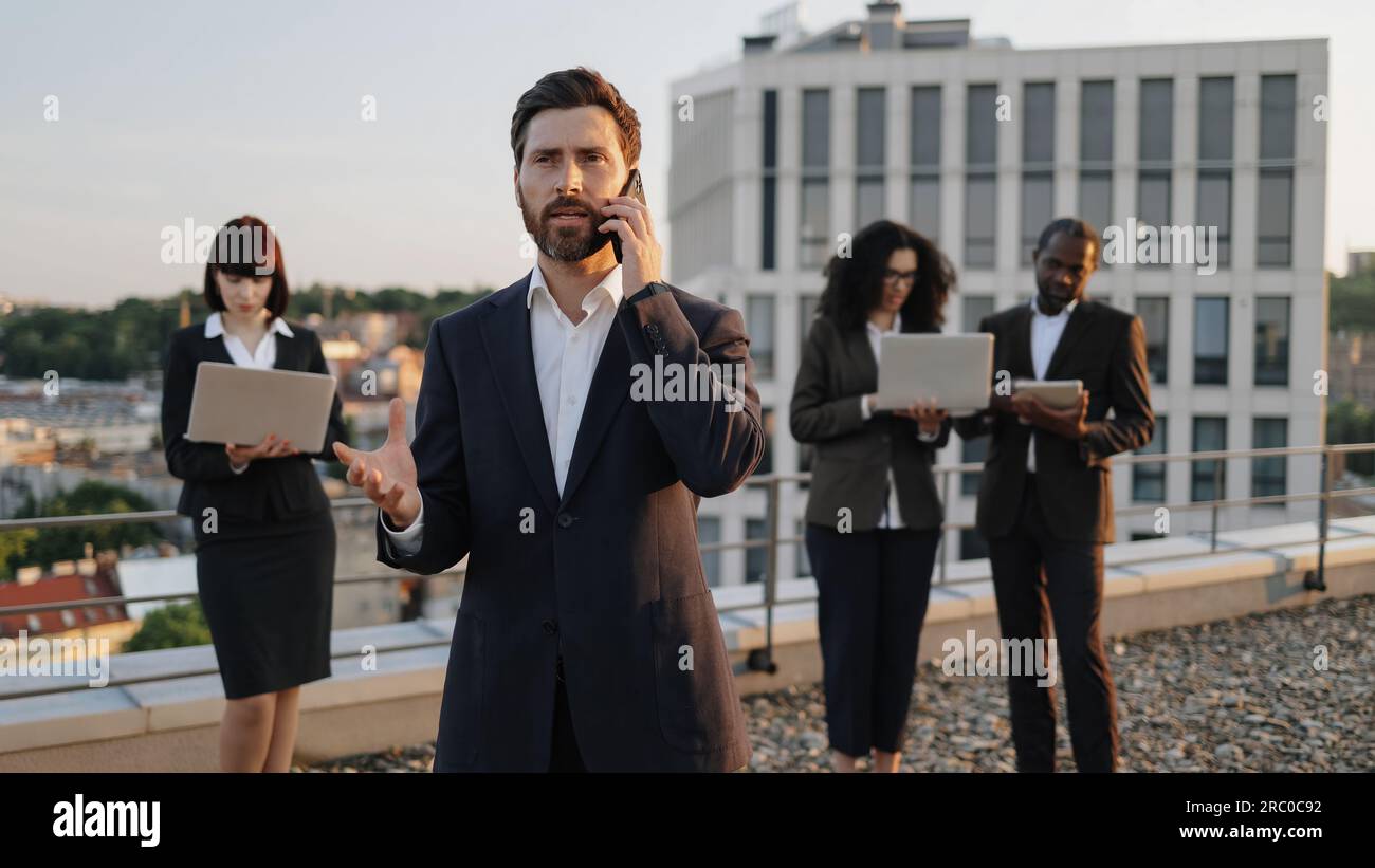 Business investor talking on smartphone while his colleagues working on ...