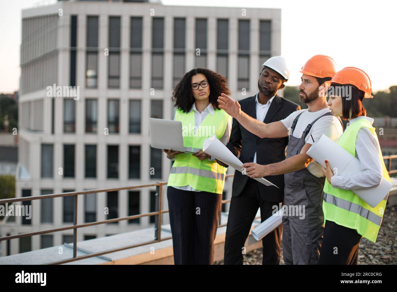 Four multiracial engineers with technical drawings and laptop ...