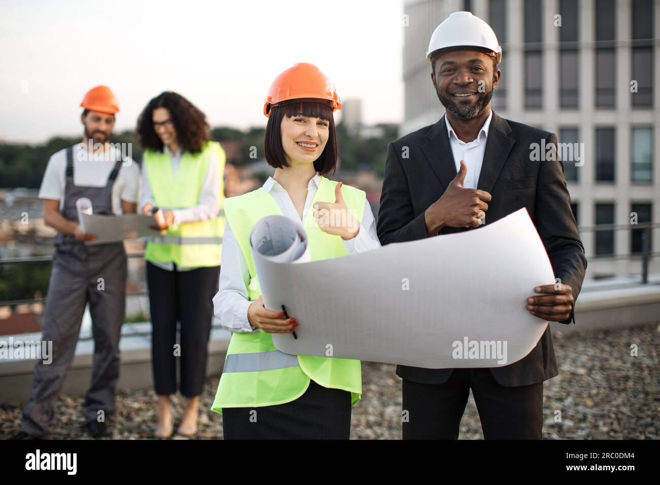 Attractive caucasian lady and african american man holding construction ...