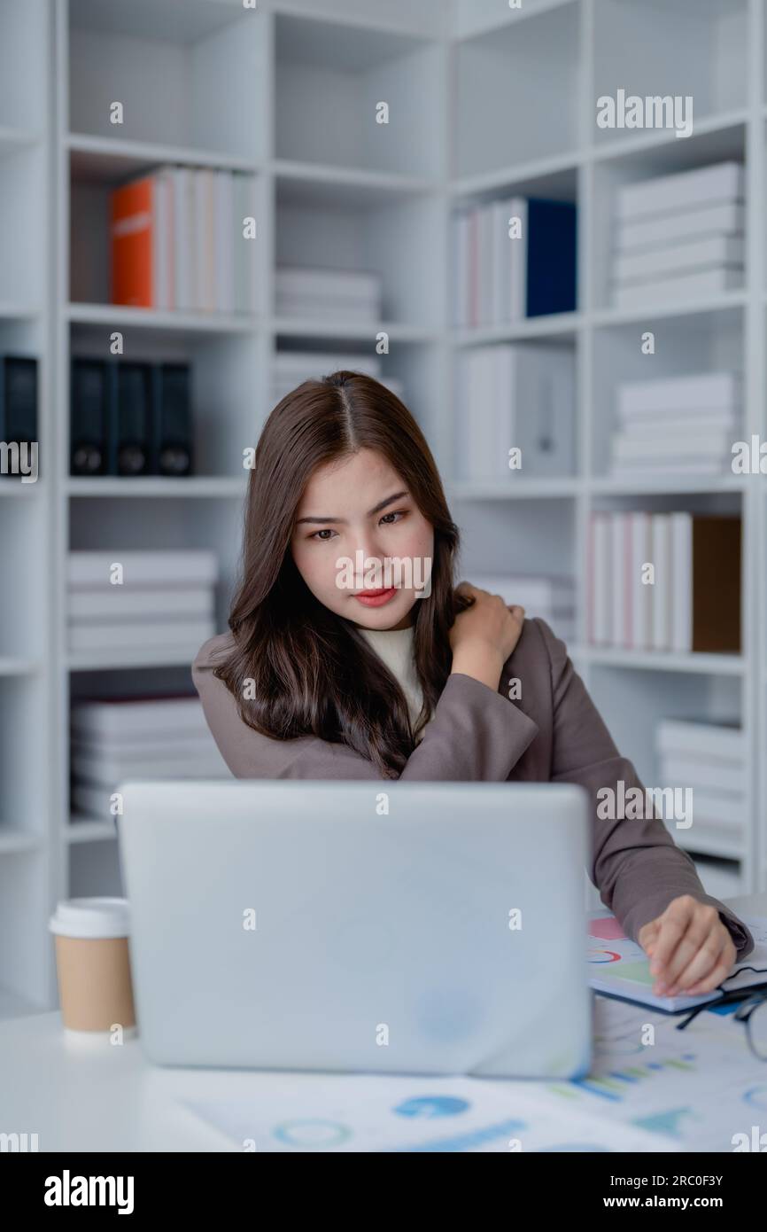 Portrait of a young Asian woman suffering from acute headache and ...
