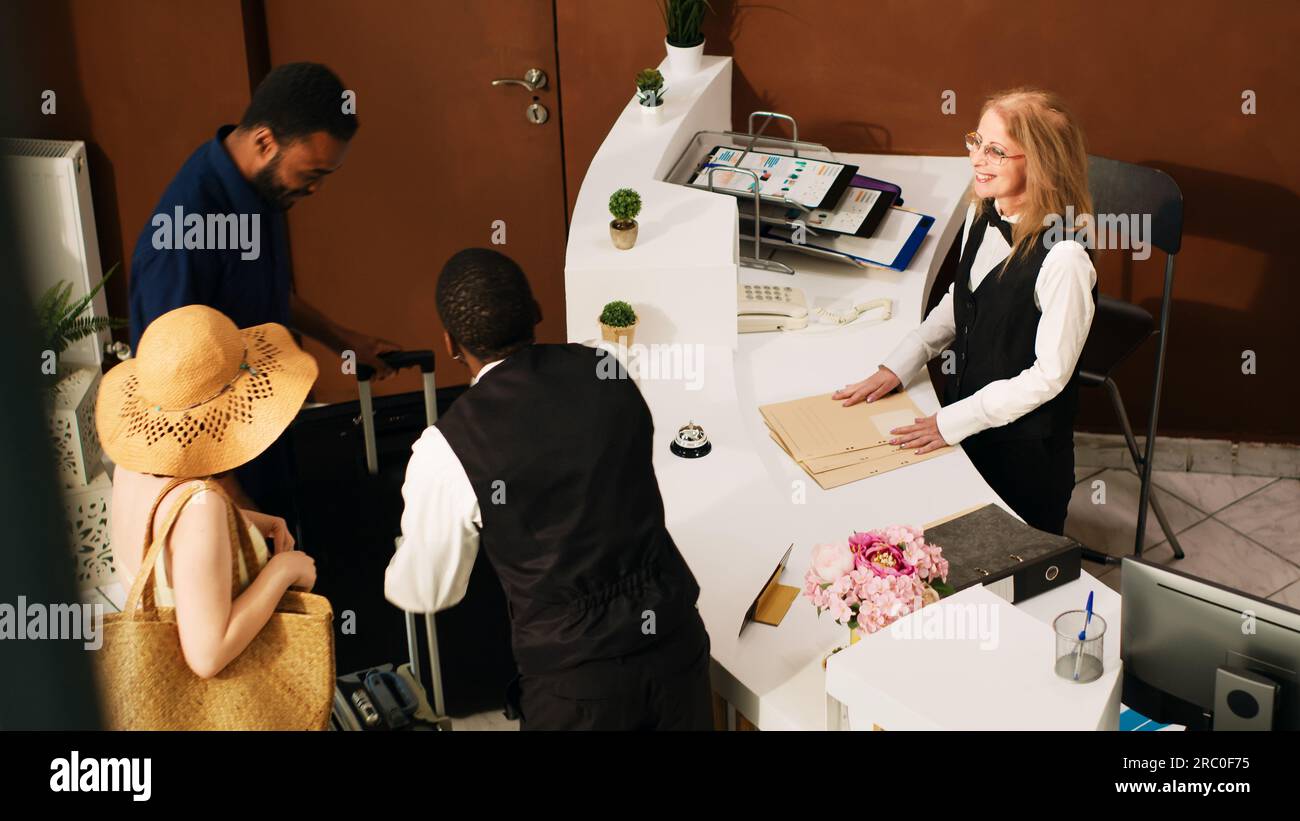 People arriving at hotel front desk, preparing to do check in at ...