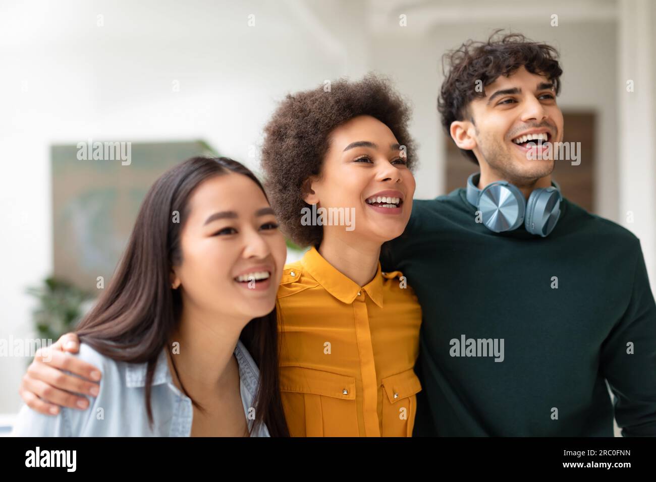 Happy diverse friends embracing looking aside and smiling, enjoying ...