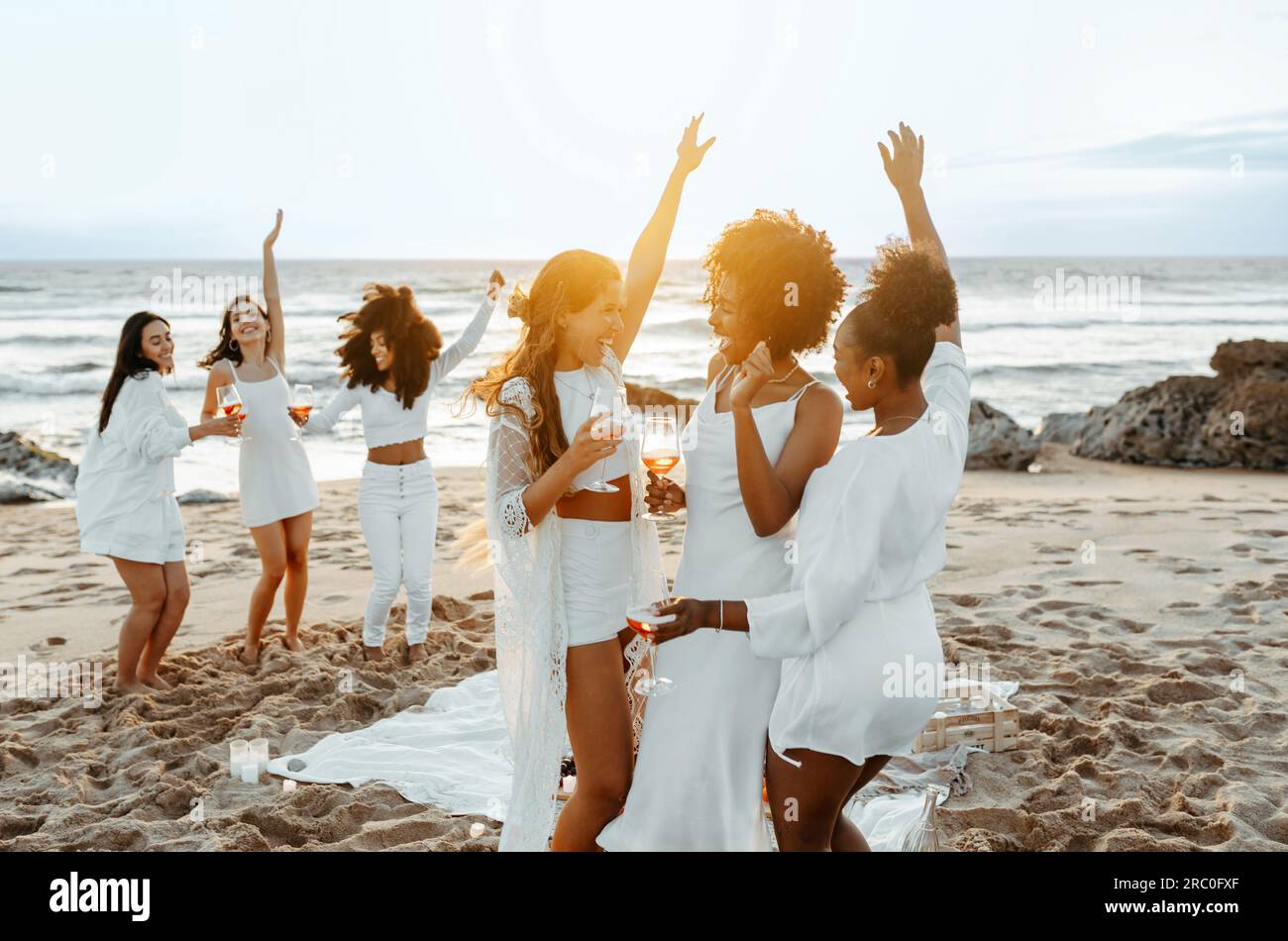 Group of happy young ladies dancing at the beach on beautiful summer ...