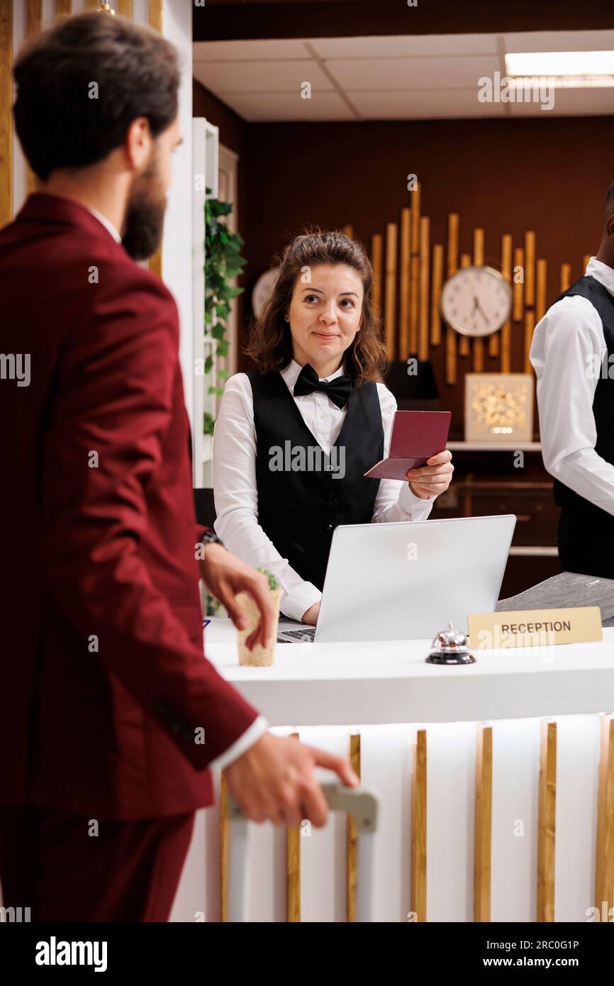 Employee checking guest passport to validate online booking reservation ...