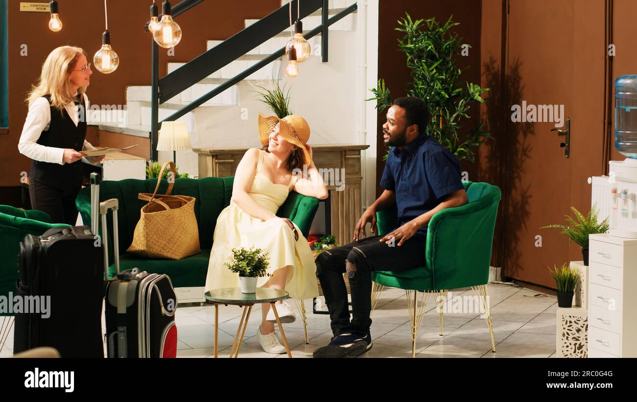 Hotel staff talking to guests in lobby, offering luxury services to ...