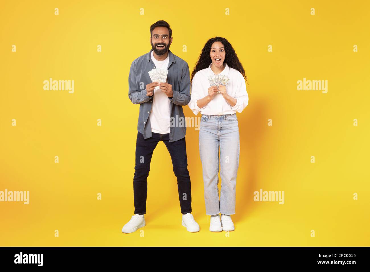 Cheerful Arabic Couple Holding Money Cash Standing On Yellow Background ...