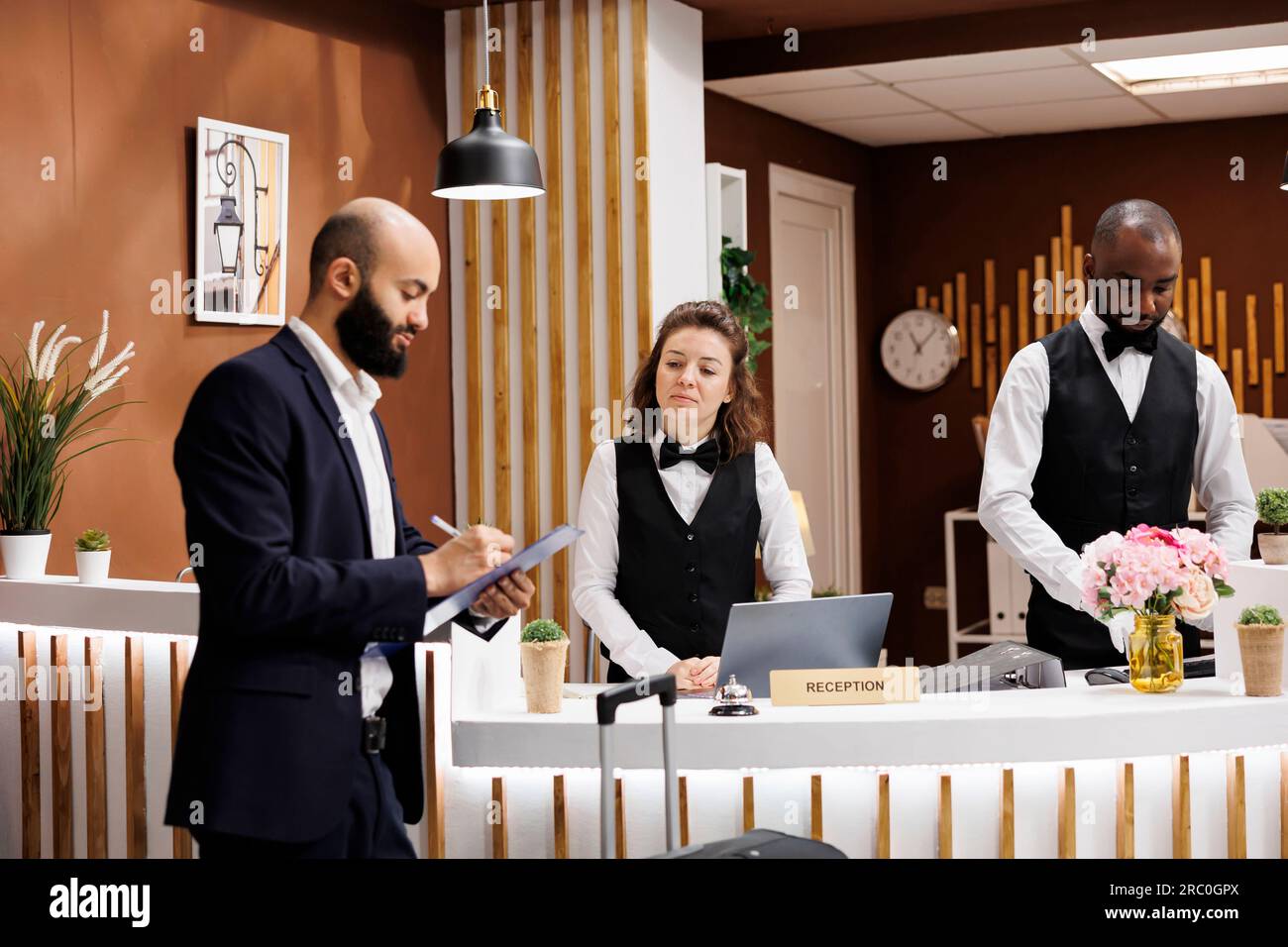 Entrepreneur arrive in hotel reception, signing forms to register and ...