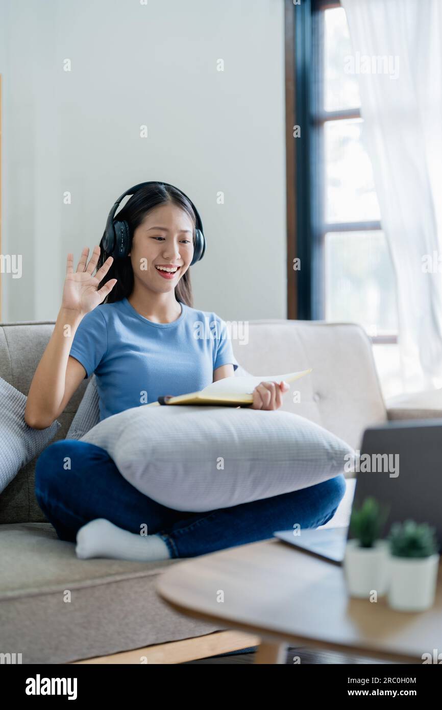 Asian young business woman is sitting on the sofa is wearing headphones ...