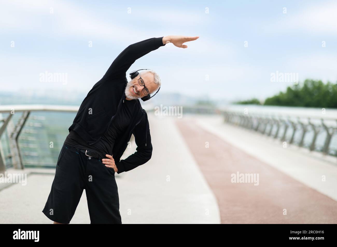 Positive well-fit senior man have outdoor workout, stretching body ...