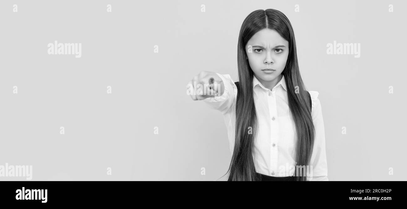 Serious frown school girl point pen putting out hand yellow background ...