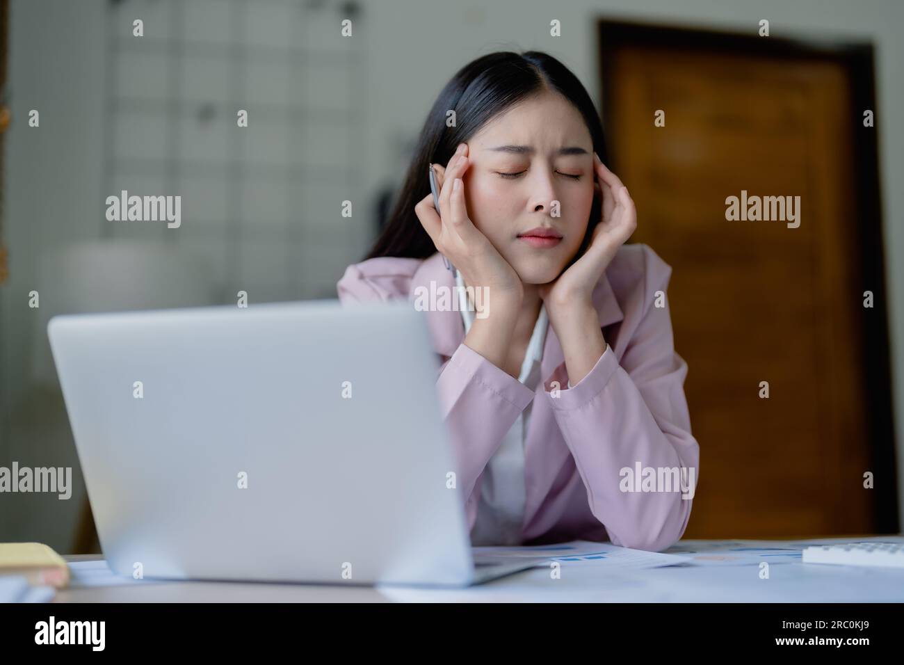 Portrait of a young Asian woman showing acute headache from sitting for ...