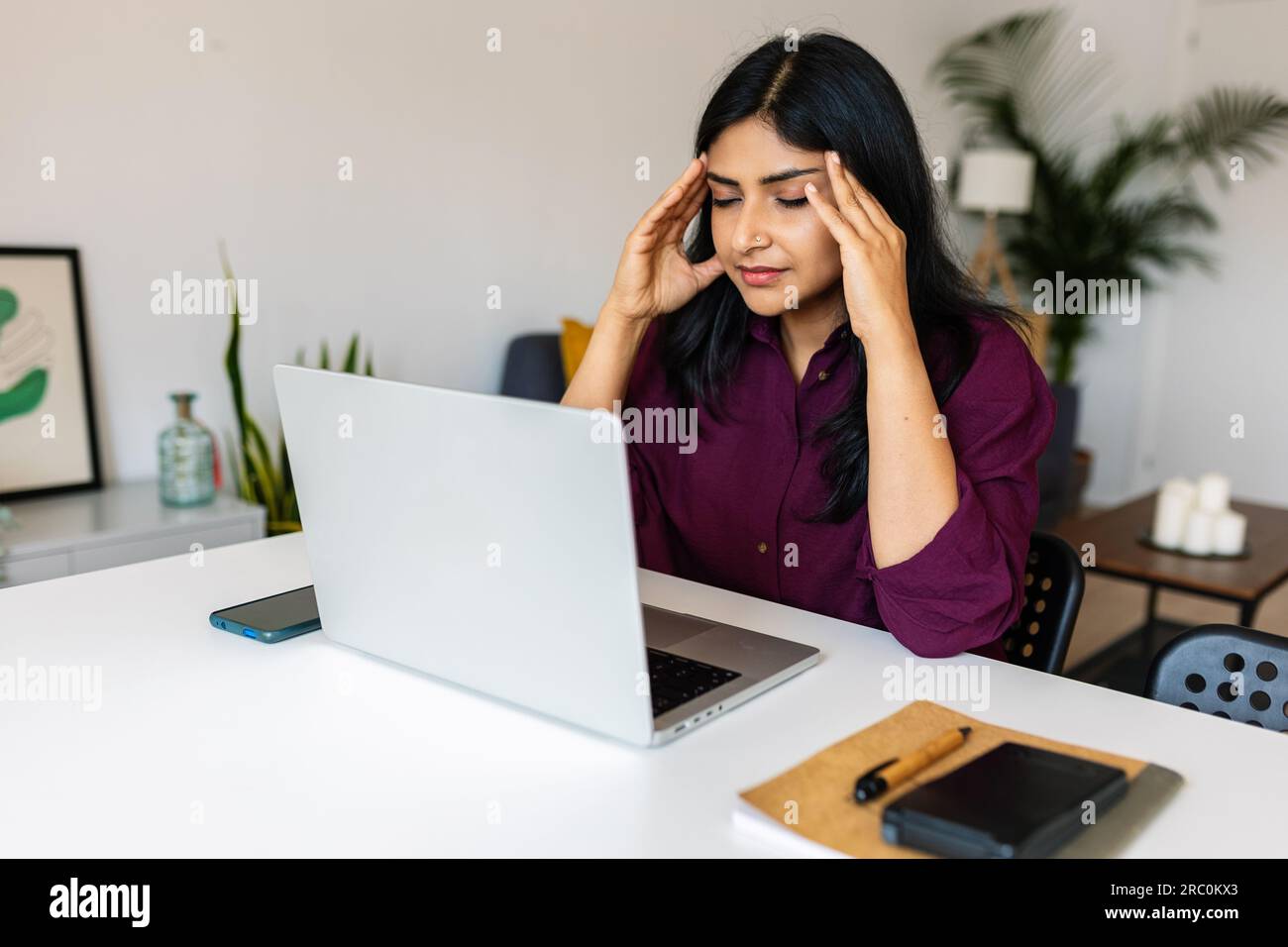 Young indian woman suffering headache or migraine while working on ...