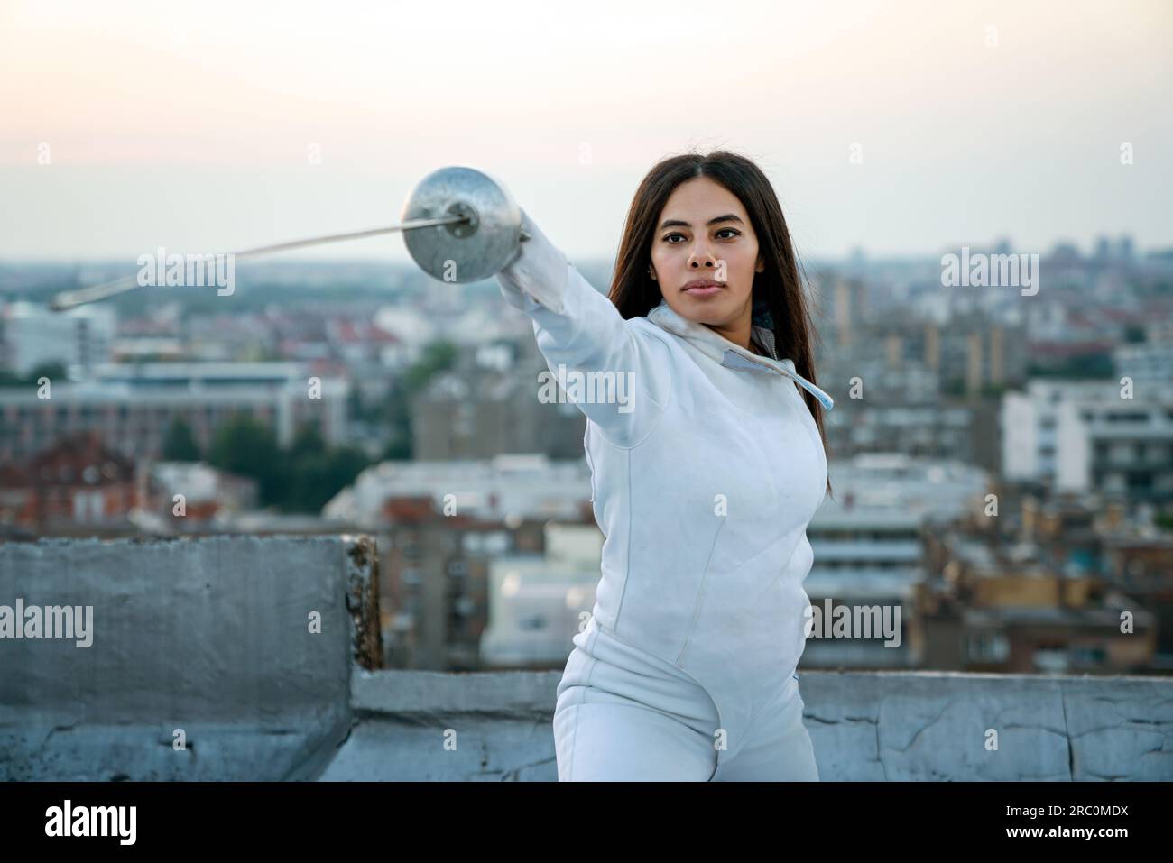 Woman in white fencing costume practicing outdoors. Sport, professional coach, healthy lifestyle ...
