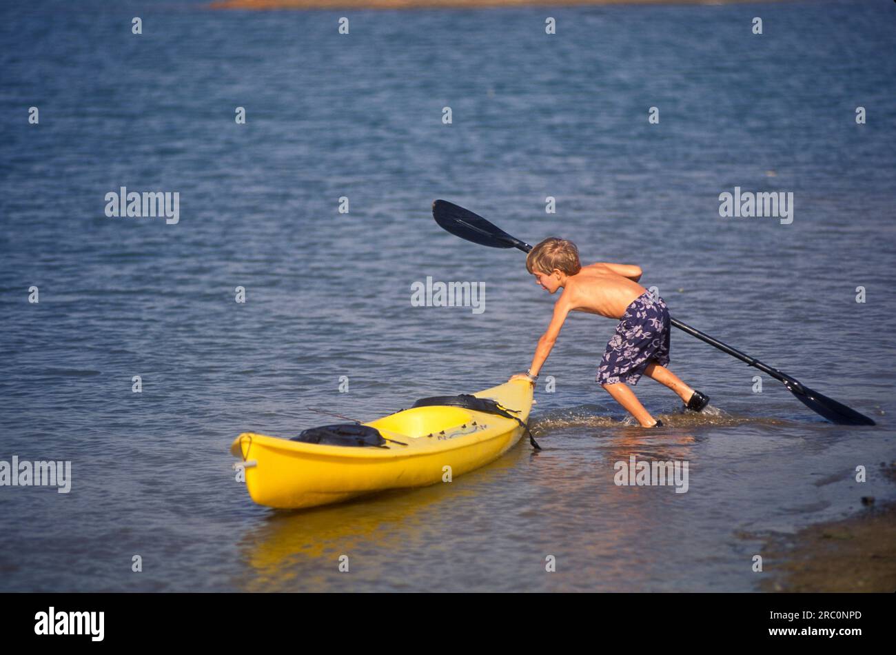 Boy bringing the kayak in the water of a lake, Venezuela Stock Photo ...