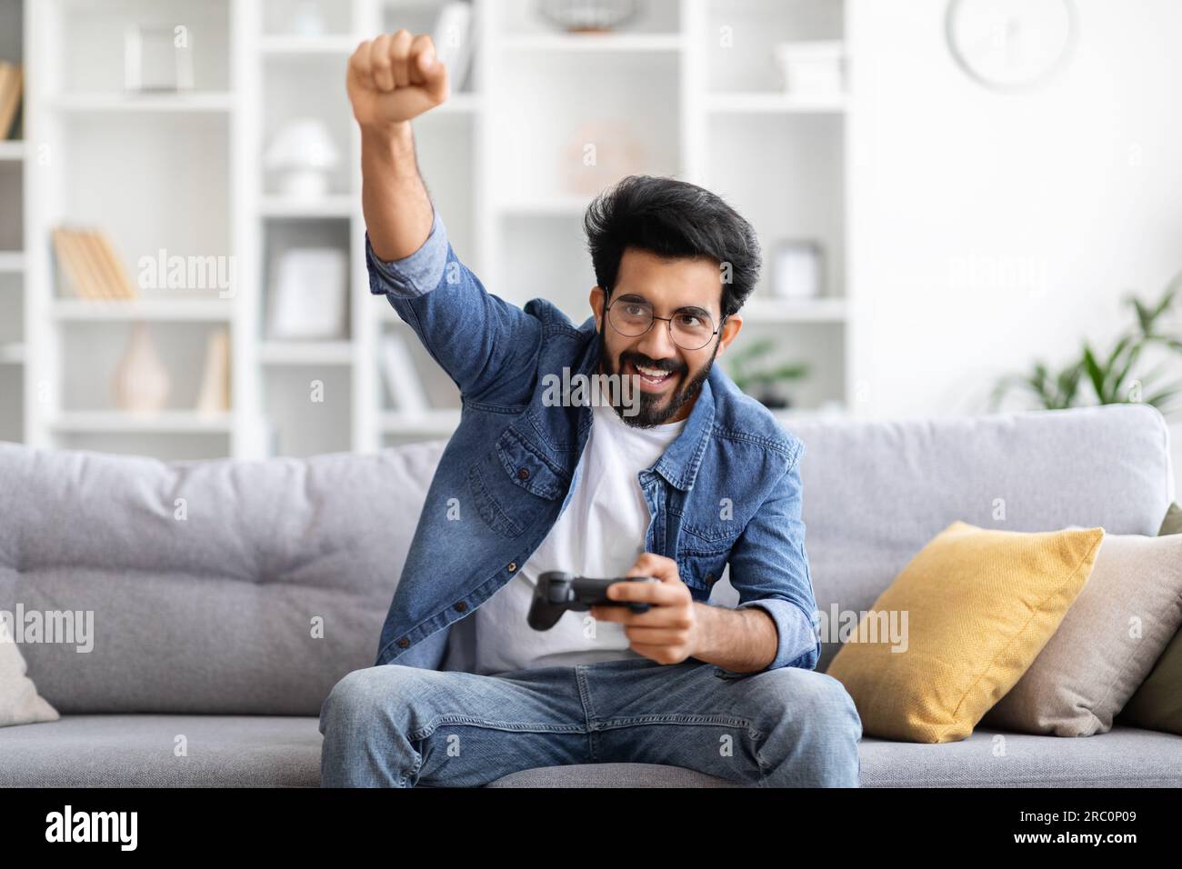 Overjoyed indian man playing video game with joystick at home Stock ...