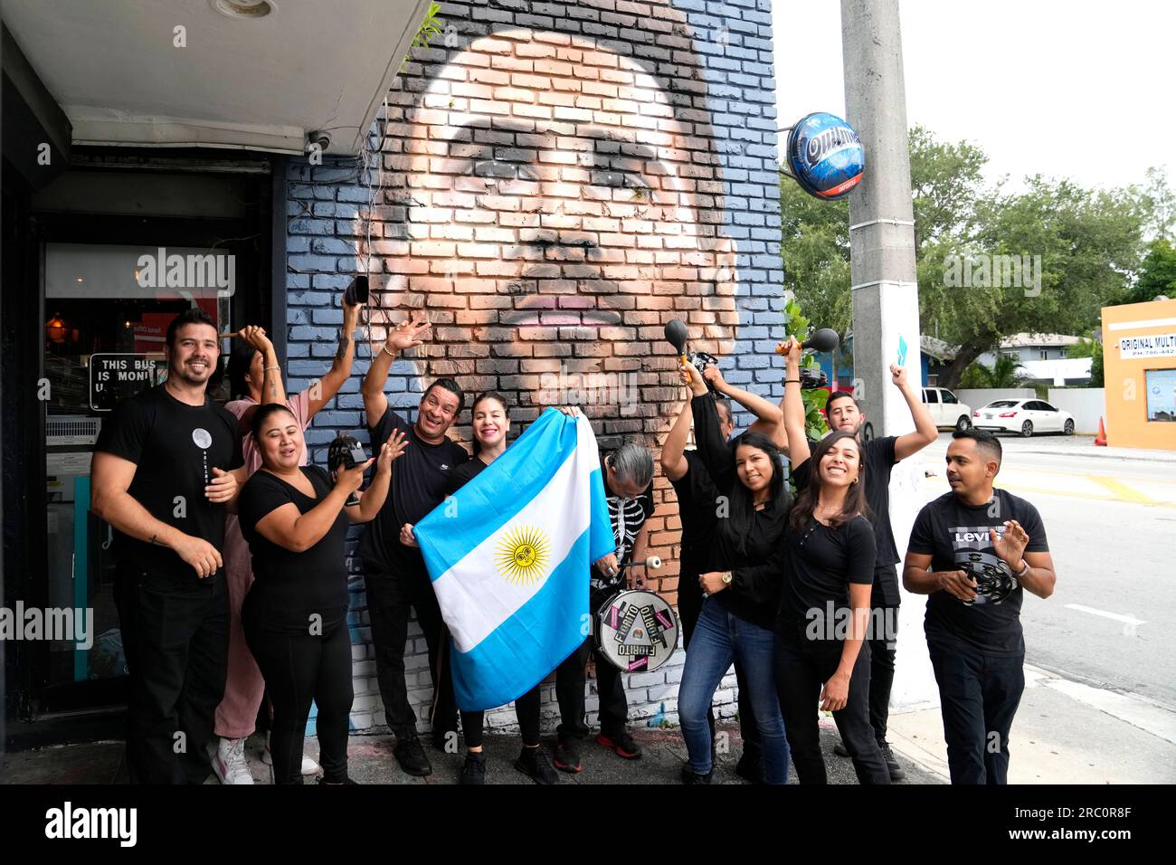 Staff at the Fiorito restaurant pose in front of a mural of Lionel ...