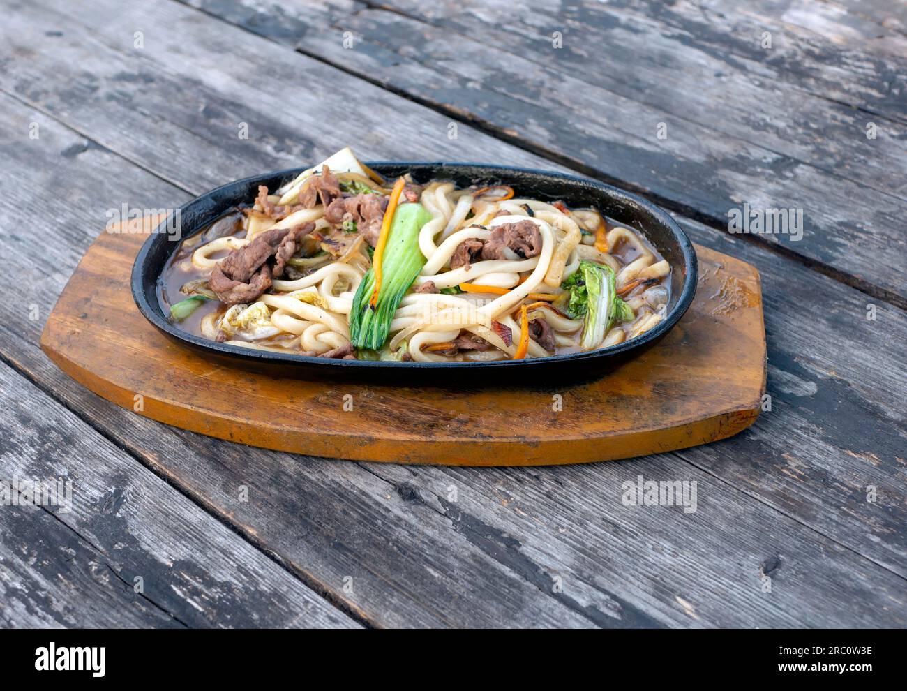 Hot delicious beef udon noodle, hot plate on an old teak wood table ...