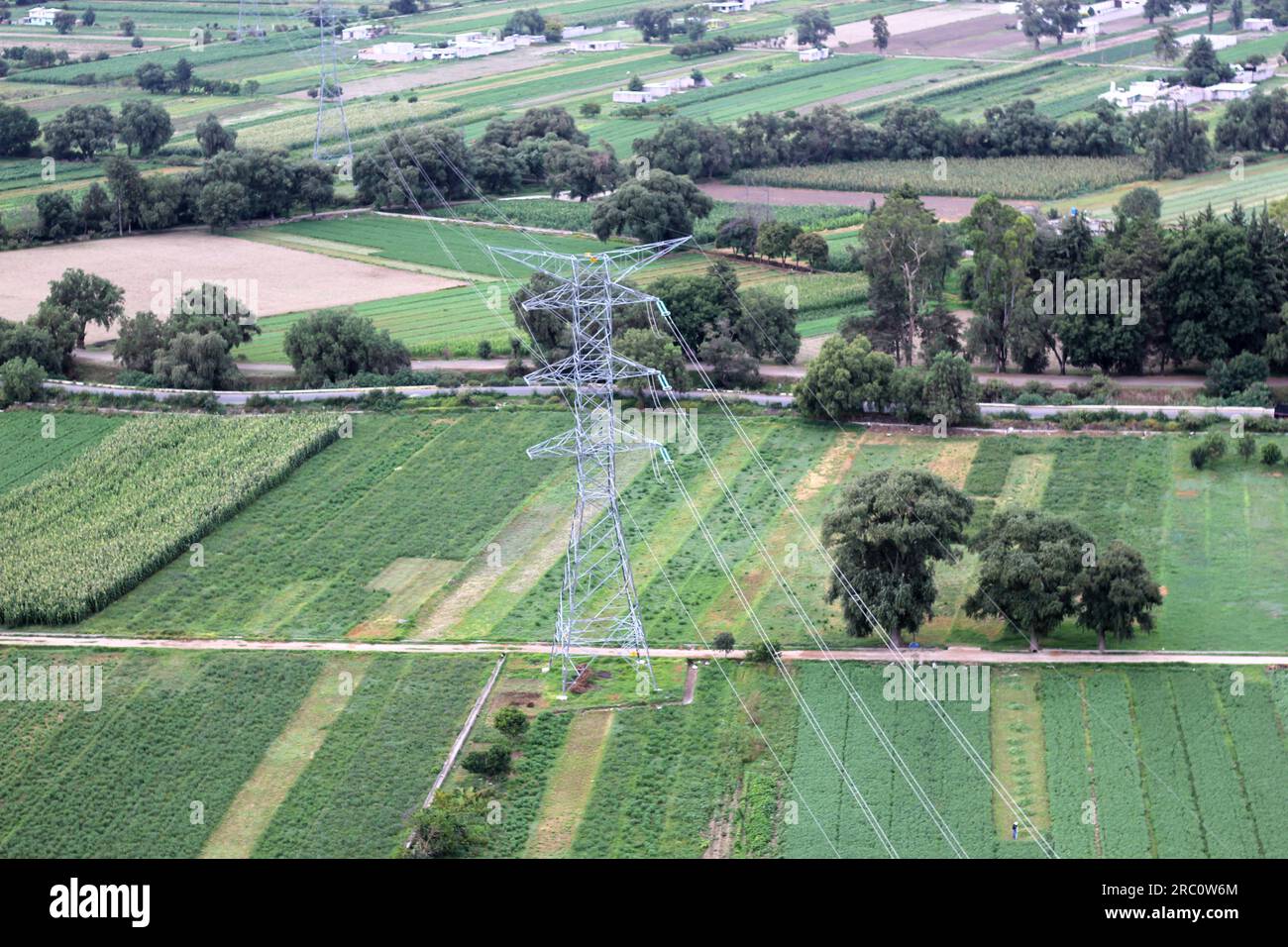 View of electric tower and high voltage cables in the middle of green ...