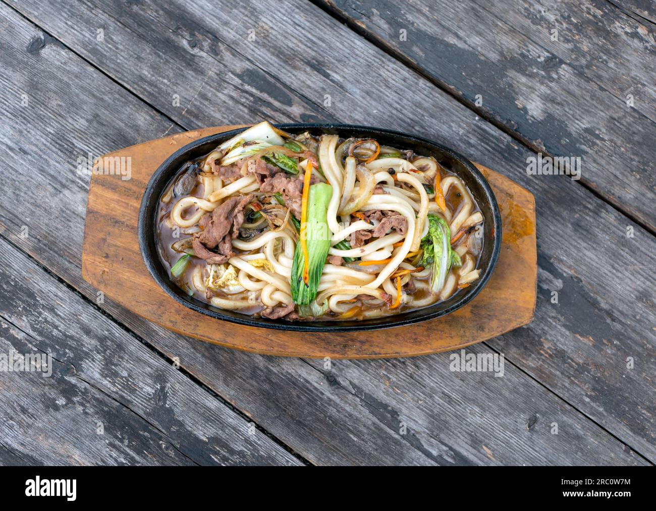 Hot delicious beef udon noodle, hot plate on an old teak wood table ...