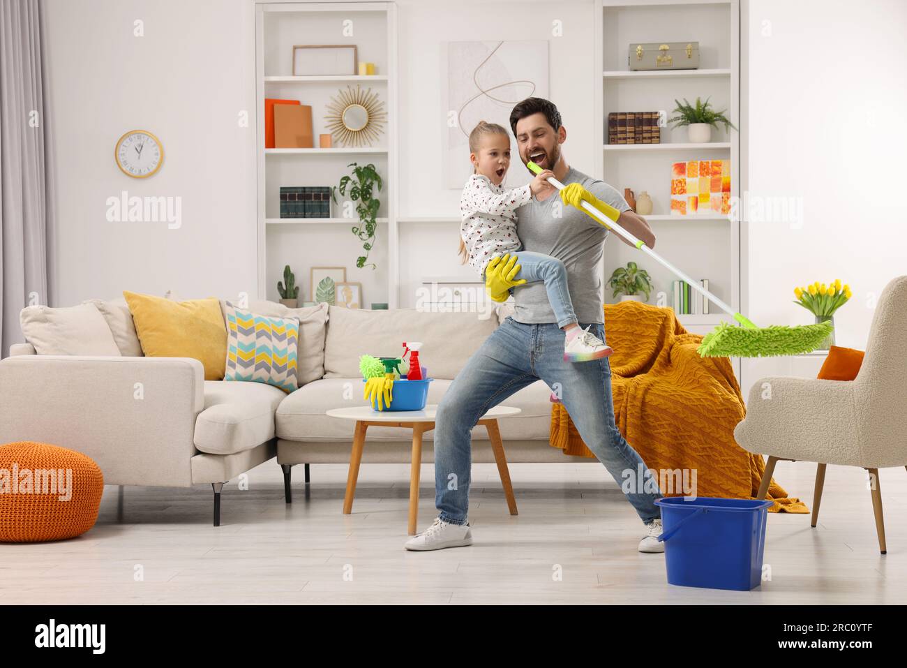 Spring cleaning. Father and daughter singing while tidying up together ...