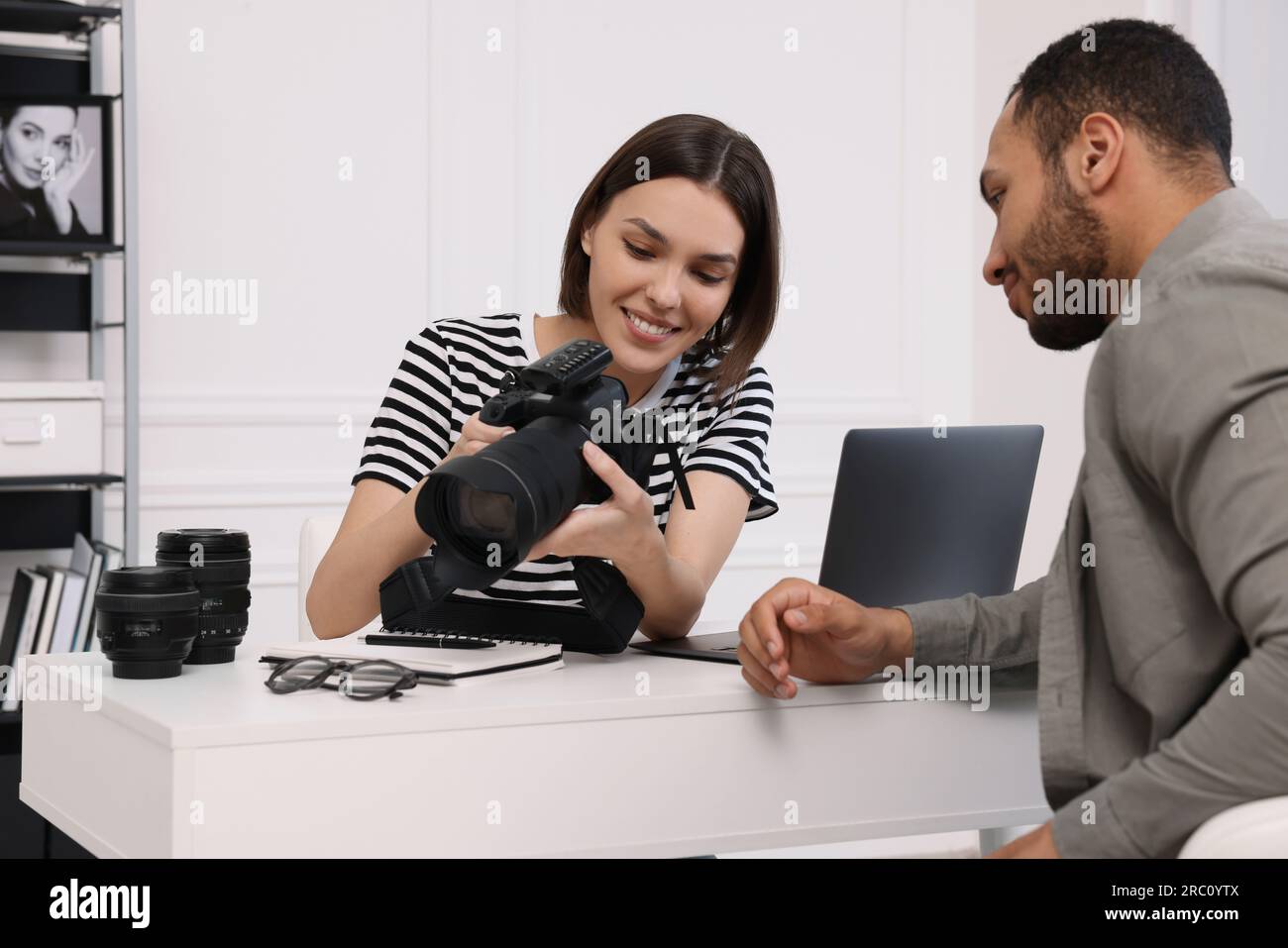 Young professional photographer showing camera to man in modern photo ...