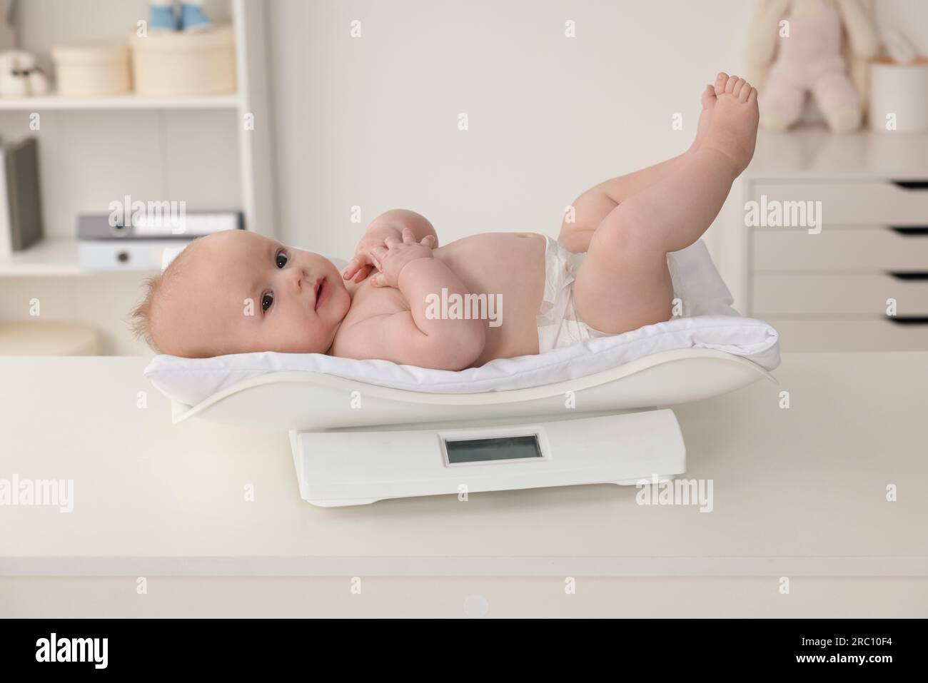 Cute little baby lying on scales in clinic Stock Photo - Alamy