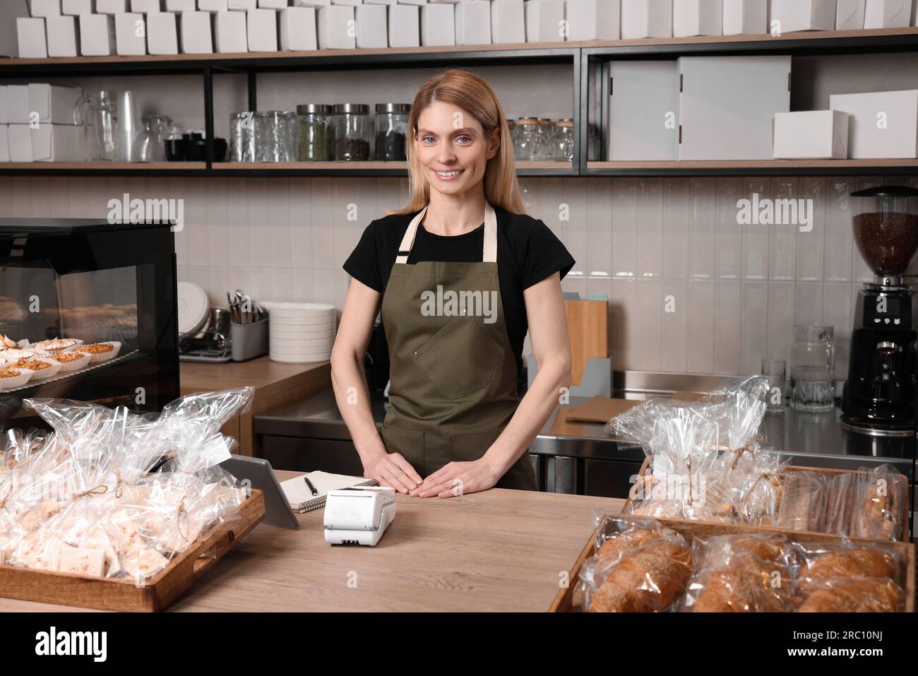 Happy seller at cashier desk in bakery shop Stock Photo - Alamy