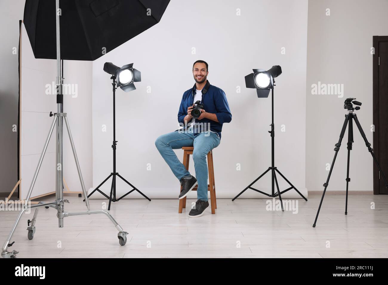 Young professional photographer with camera in modern photo studio ...