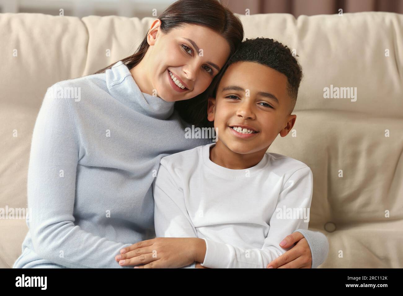 Mother with her African American son on sofa. International family ...