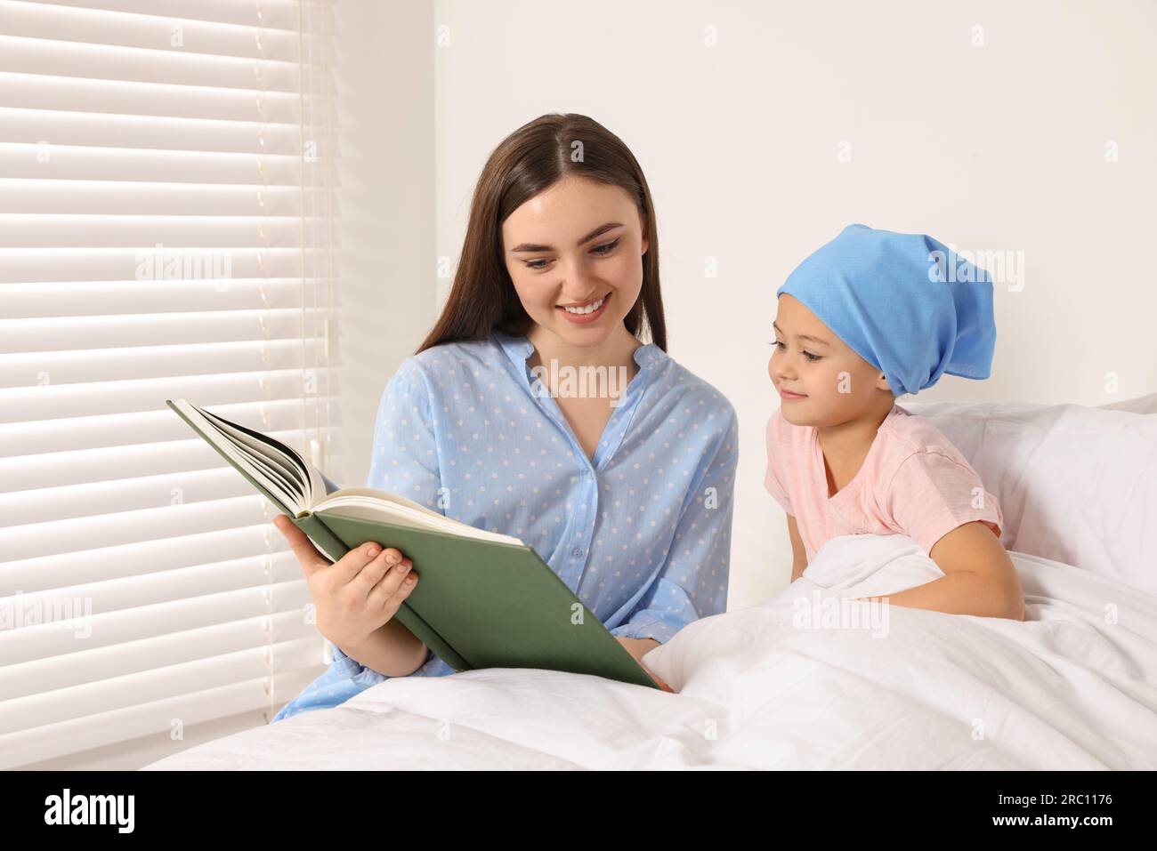 Childhood cancer. Mother and daughter reading book in hospital Stock ...