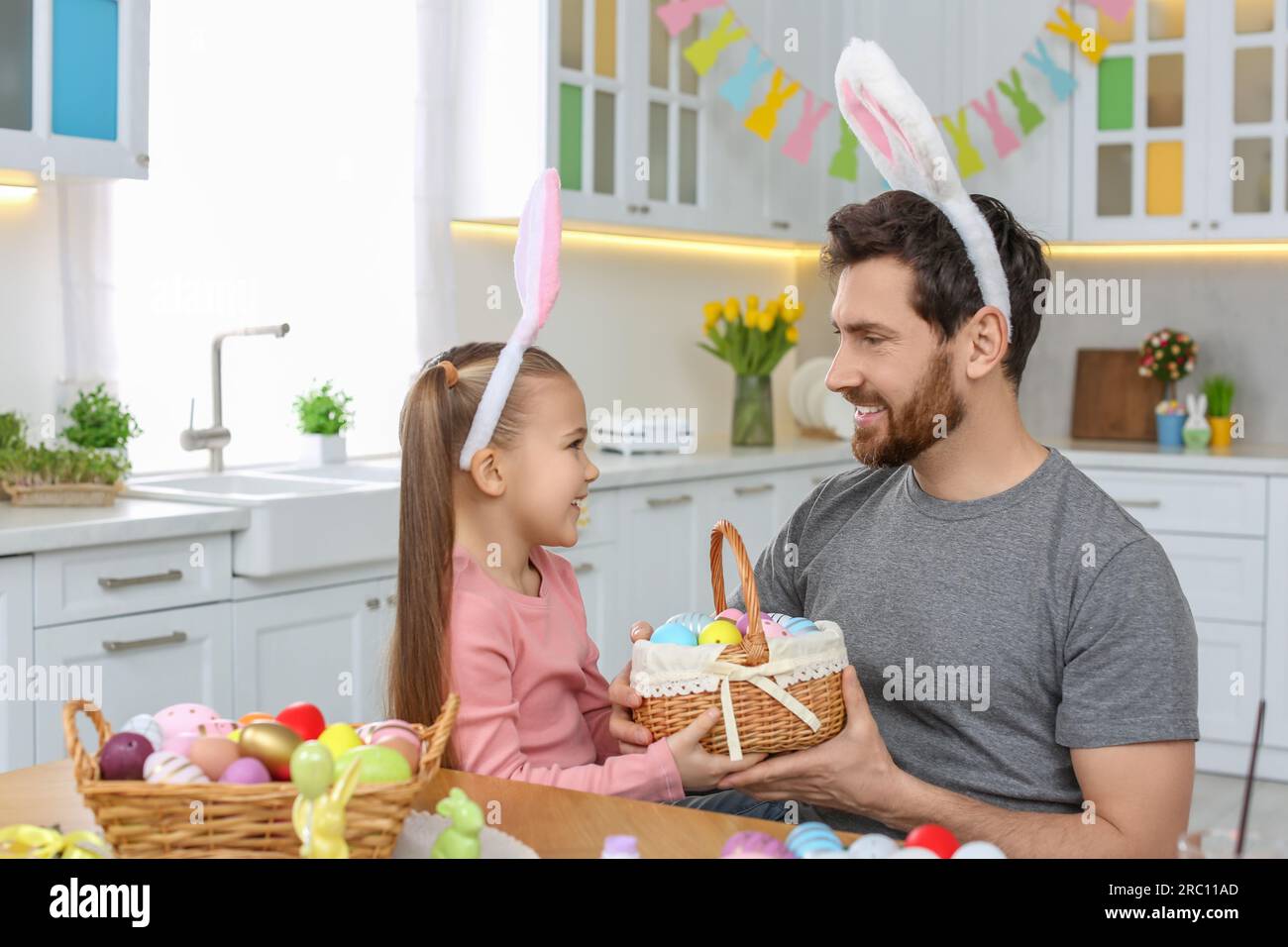 Father and his cute daughter with wicker basket full of Easter eggs in ...