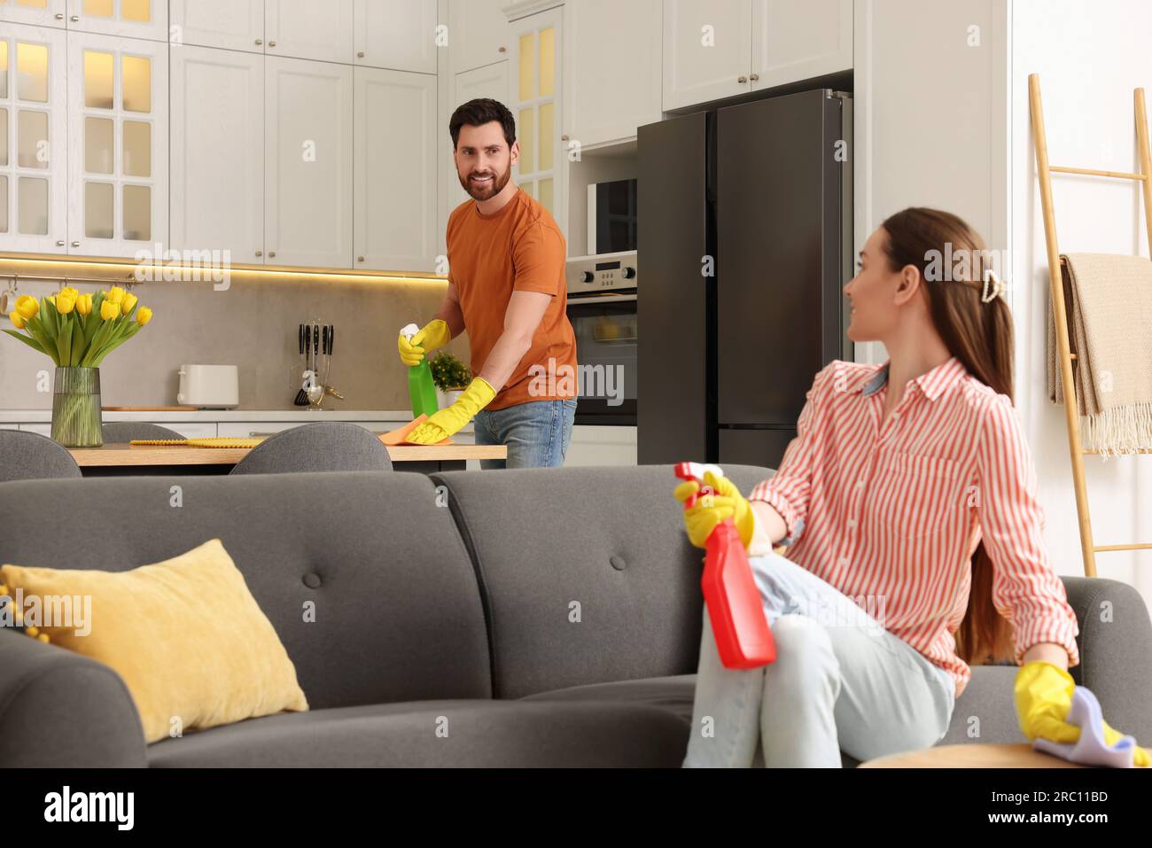 Spring cleaning. Lovely couple tidying up living room and kitchen ...