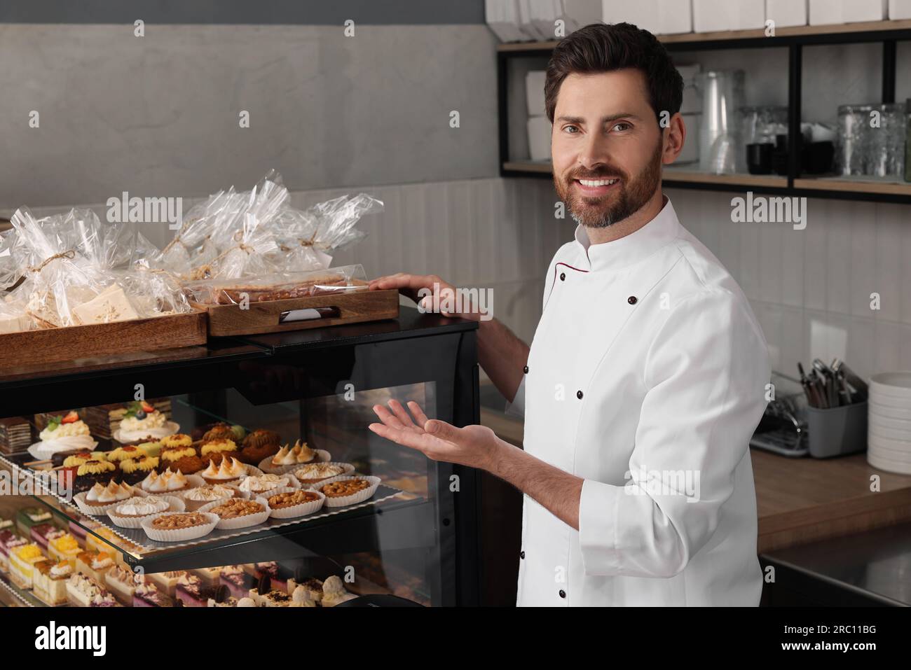 Professional baker near showcase with pastries in store Stock Photo - Alamy
