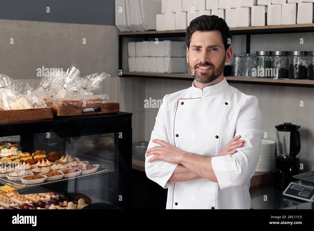 Professional baker near showcase with pastries in store Stock Photo - Alamy