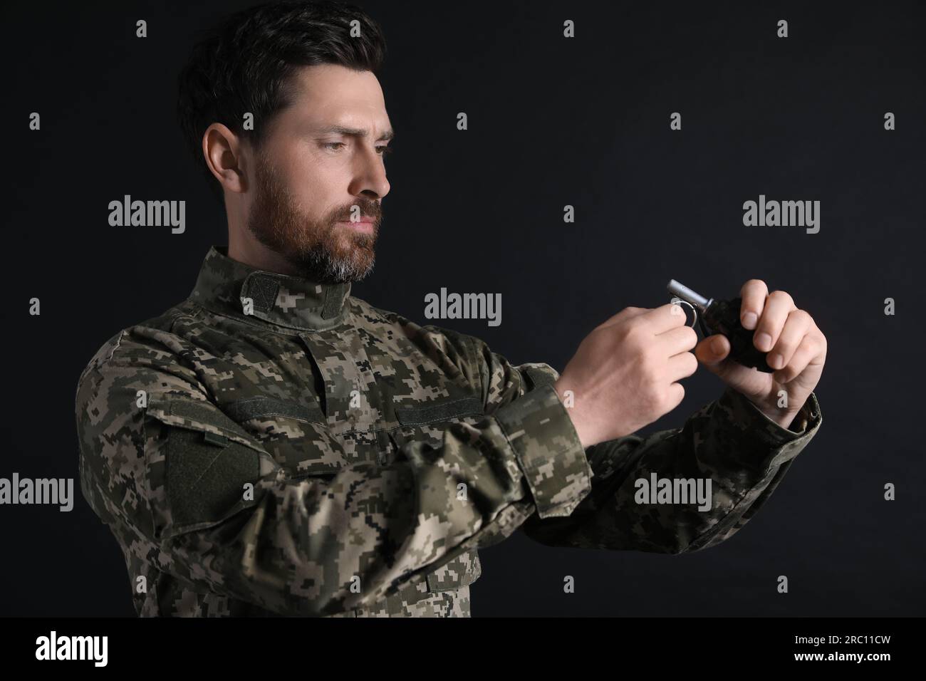 Soldier pulling safety pin out of hand grenade on black background ...