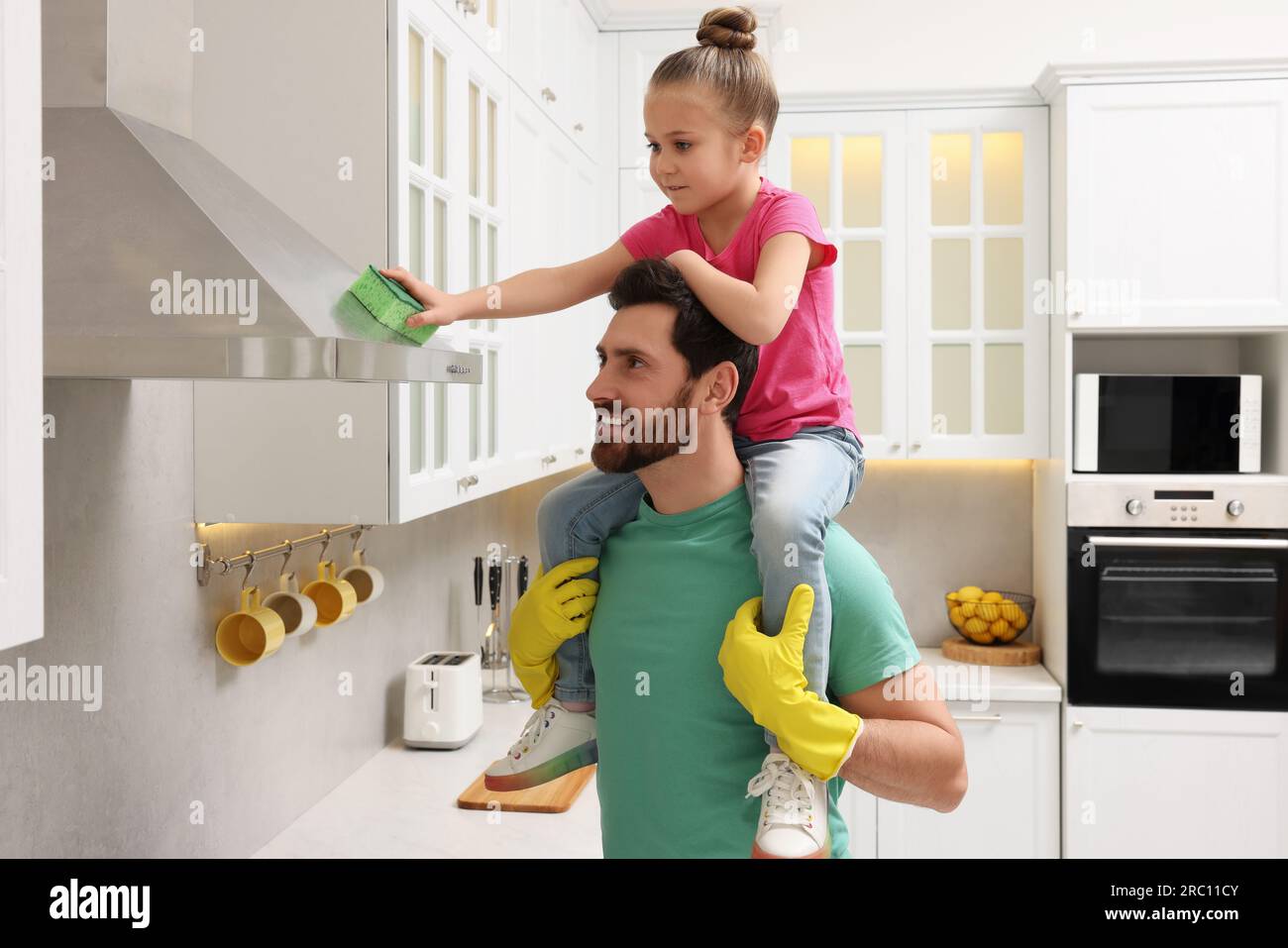 Spring cleaning. Father and daughter tidying up in kitchen together ...