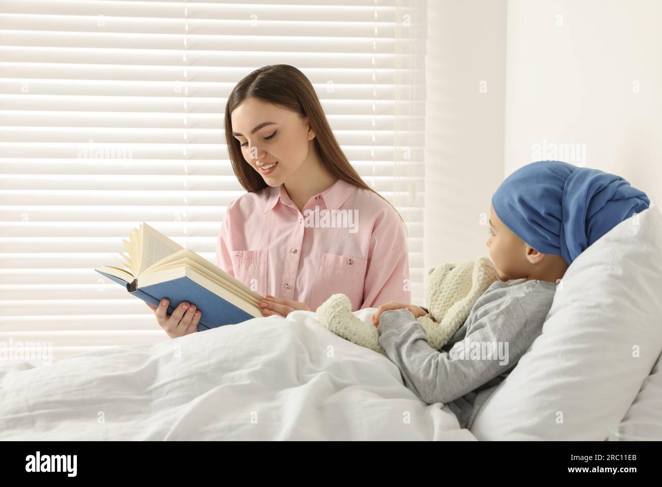 Childhood cancer. Mother reading book to daughter in hospital Stock ...