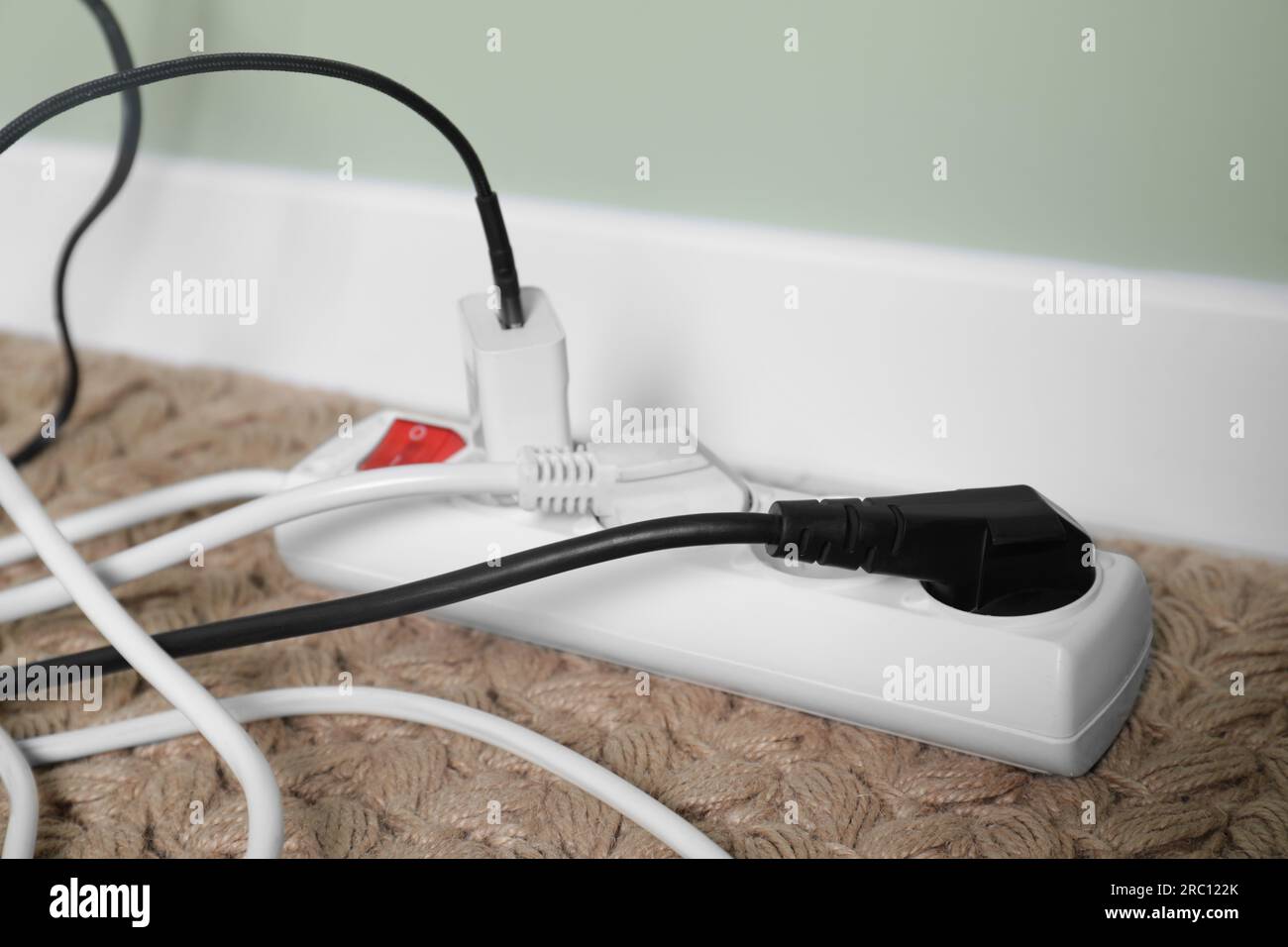 Power strip with different electrical plugs on floor indoors, closeup ...