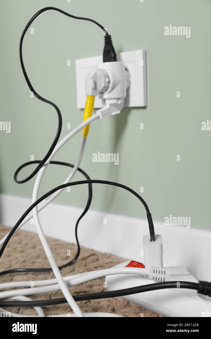 Different electrical plugs in socket and power strip on floor indoors ...