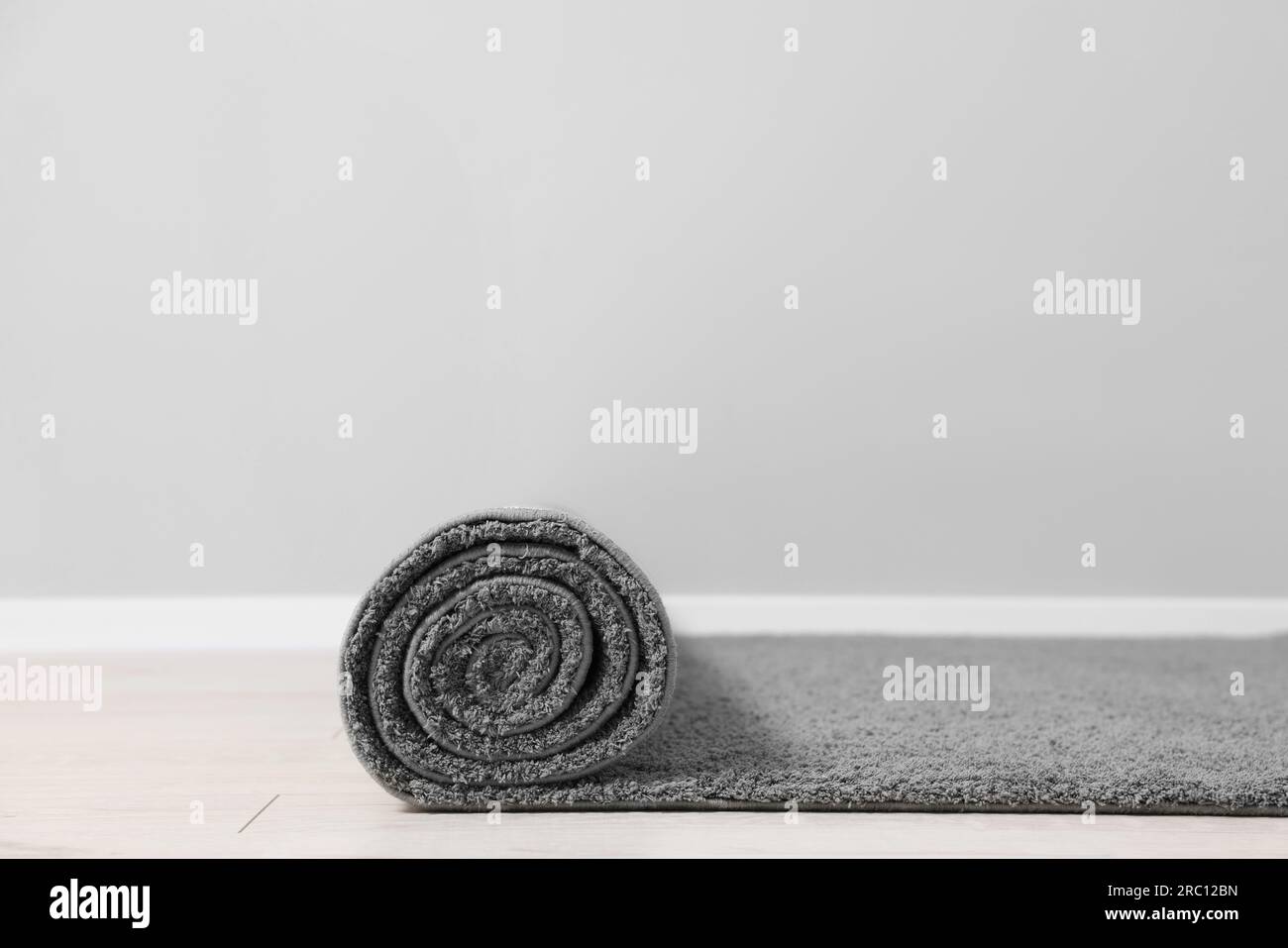 Rolled grey carpet on floor in room. Space for text Stock Photo - Alamy